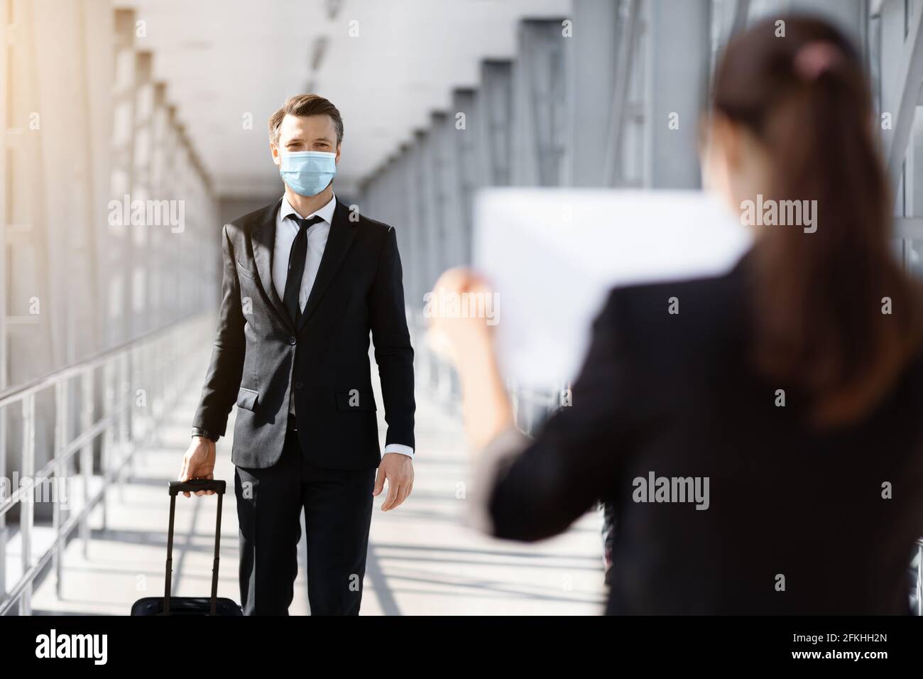 Back view of female representative meeting business partner in airport ...