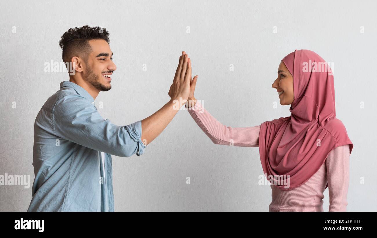 Teamwork Concept. Happy Cheerful Muslim Couple Giving High Five To Each ... Teamwork Concept. Happy Cheerful Muslim Couple Giving High Five To Each ...