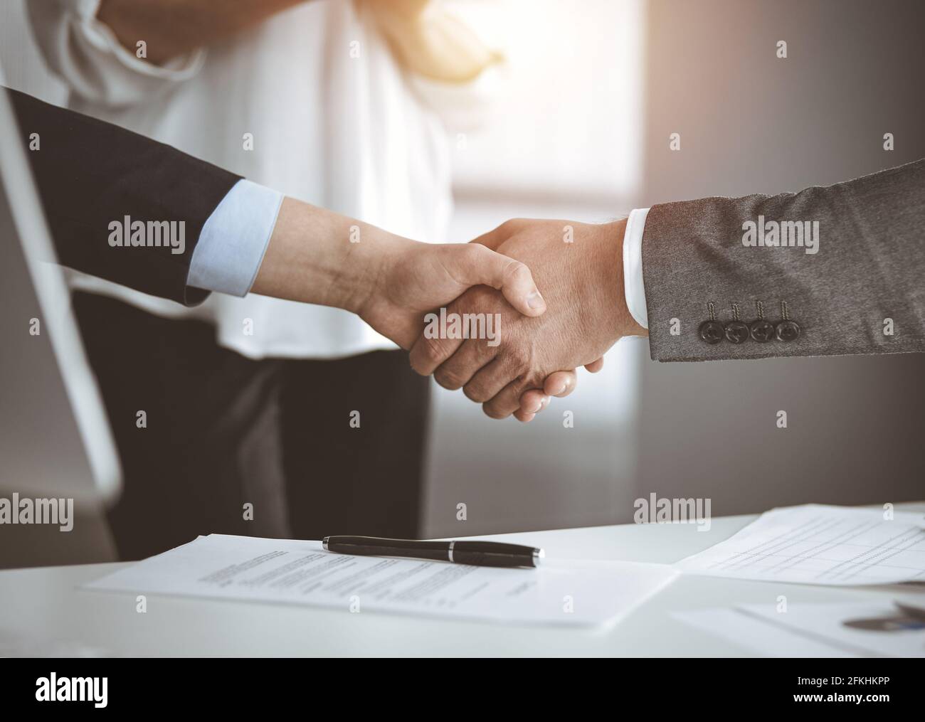 Business people shaking hands finishing contract signing in sunny ...