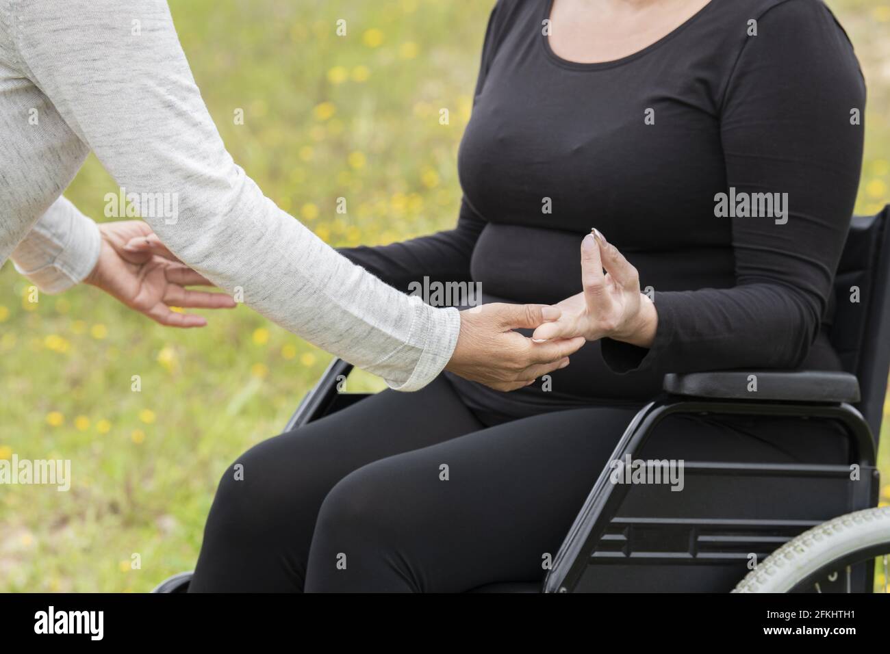 A woman sitting in a wheelchair being helped attain a meditation pose ...