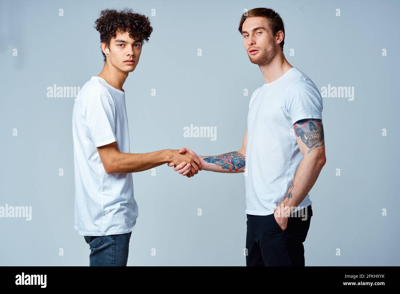 two friends hold hands in white t-shirts isolated background Stock ...
