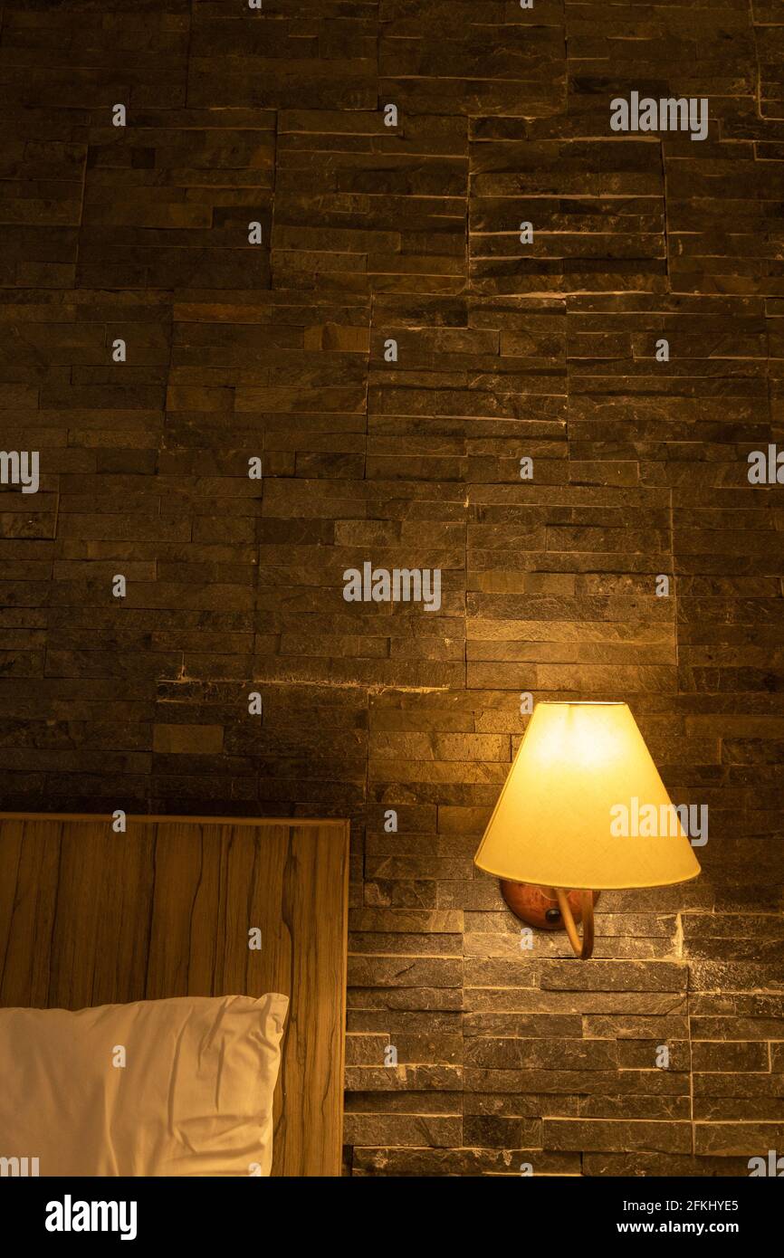 A bedside lamp shade on the wall illuminating the bed with pillow Stock ...