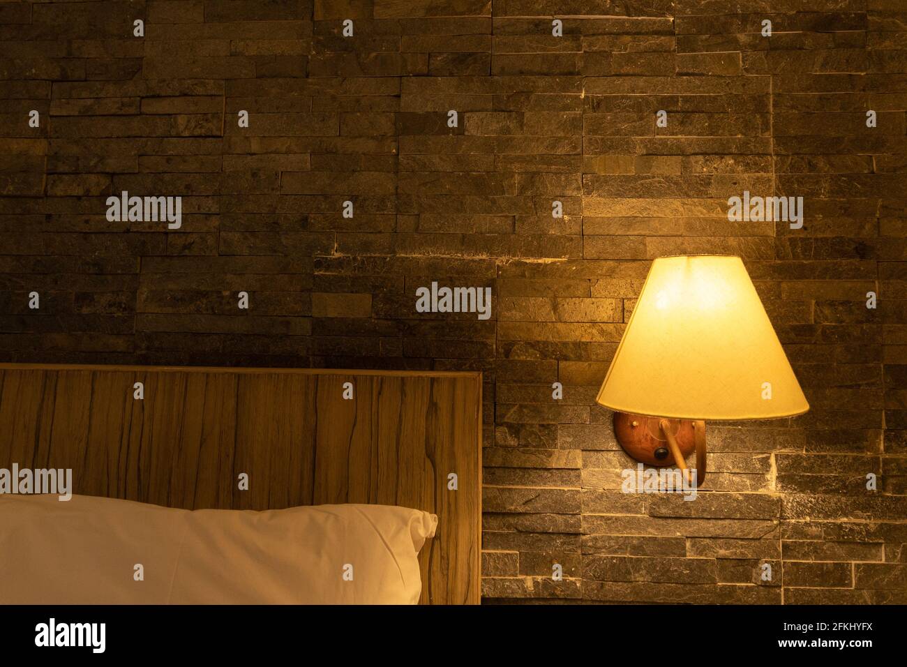 A bedside lamp shade on the wall illuminating the bed with pillow Stock ...