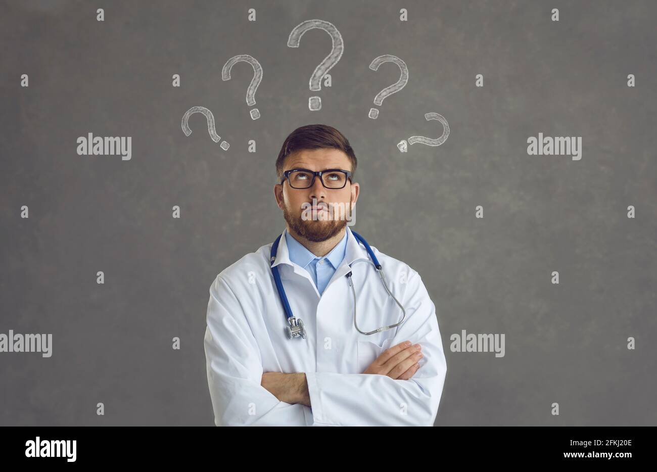 Doctor with question marks above head standing arms crossed and ...