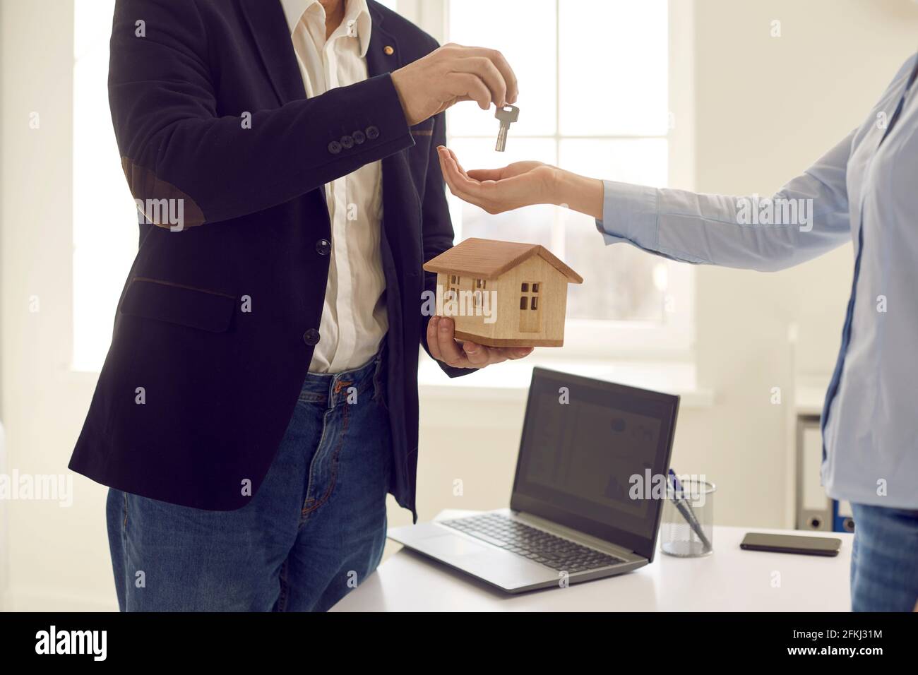 Cropped shot of real estate agent holding small house model and giving ...
