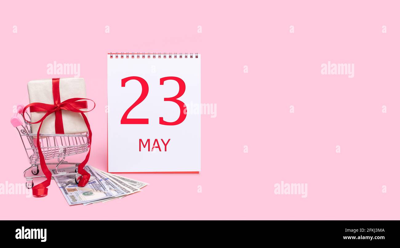 23rd day of may. A gift box in a shopping trolley, dollars and a ...
