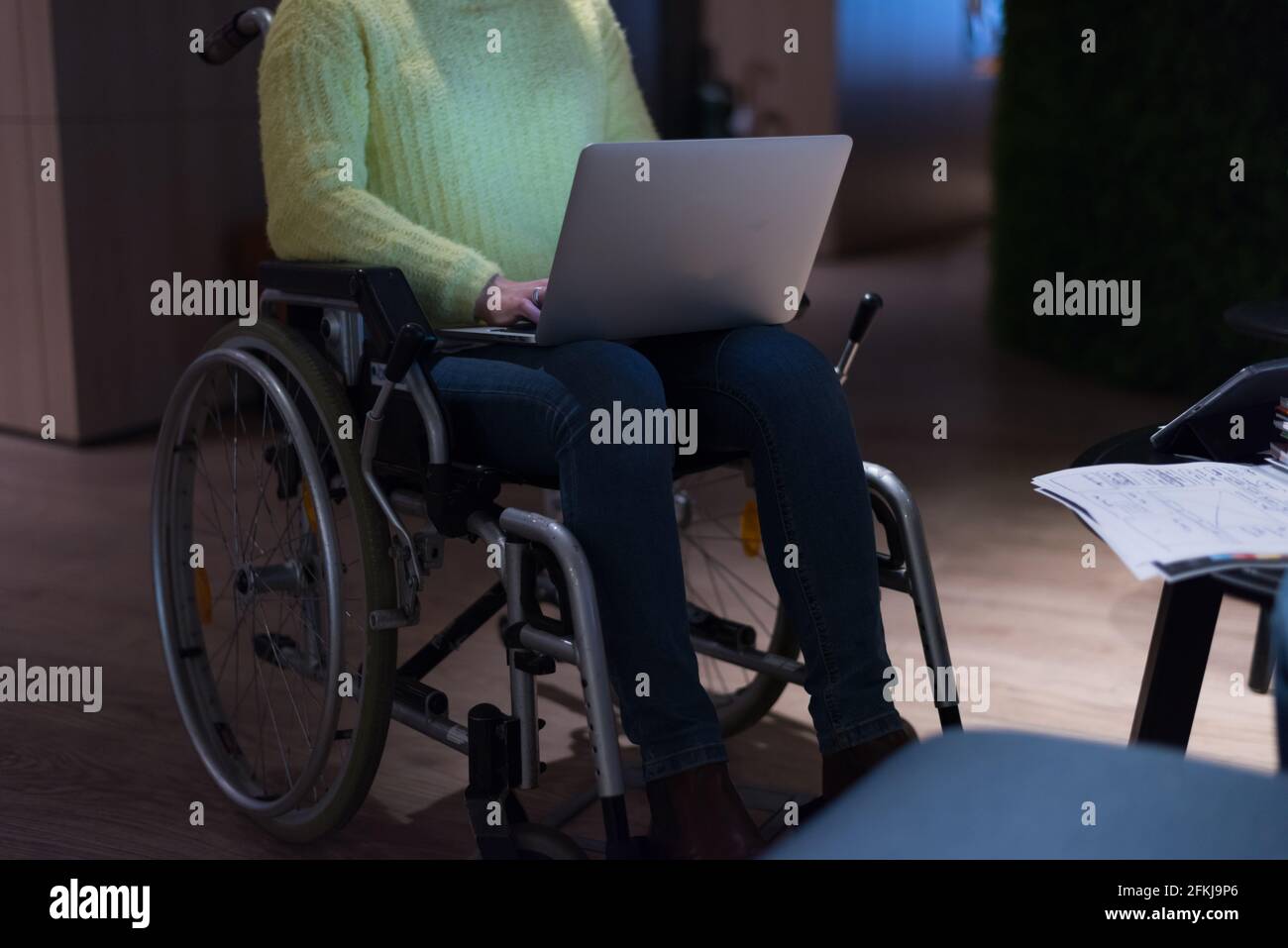 Young woman in wheelchair using computer laptop at modern workplace ...