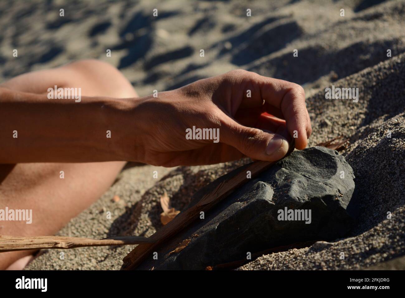making fire with twigs, stem and stone. without lighter. outdoors in ...