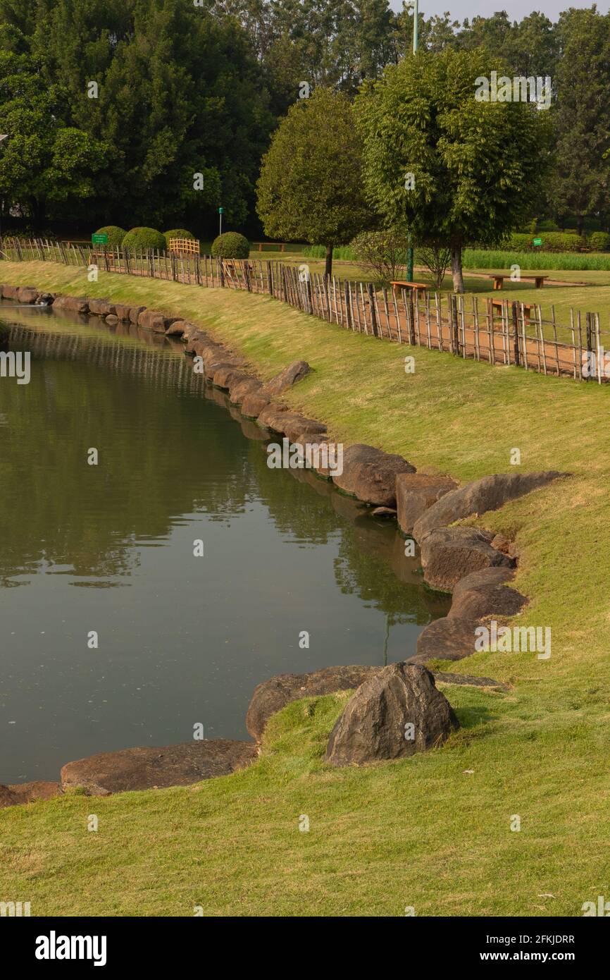 A park with a small pond, trees and lush green grass Stock Photo - Alamy