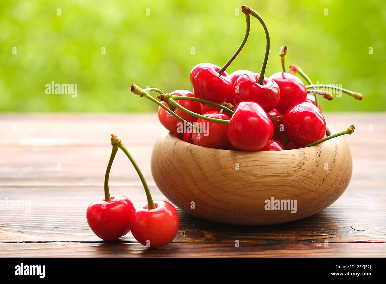Wooden bowl full of big ripe organic cherry fruit on dark brown wood ...