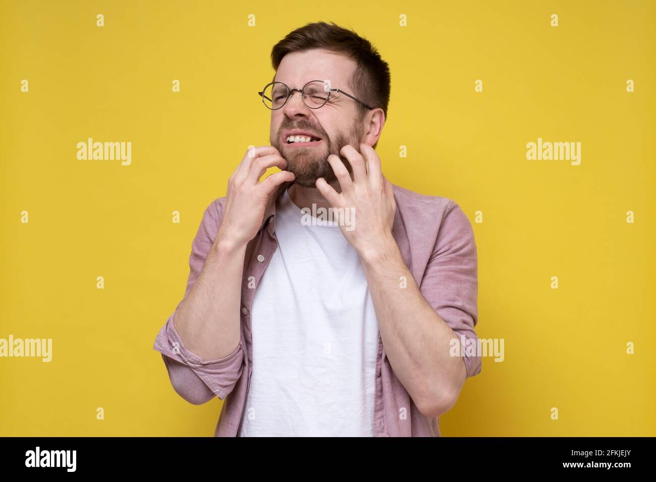 Man scratches the itchy skin on his chin with hand, he suffers from ...