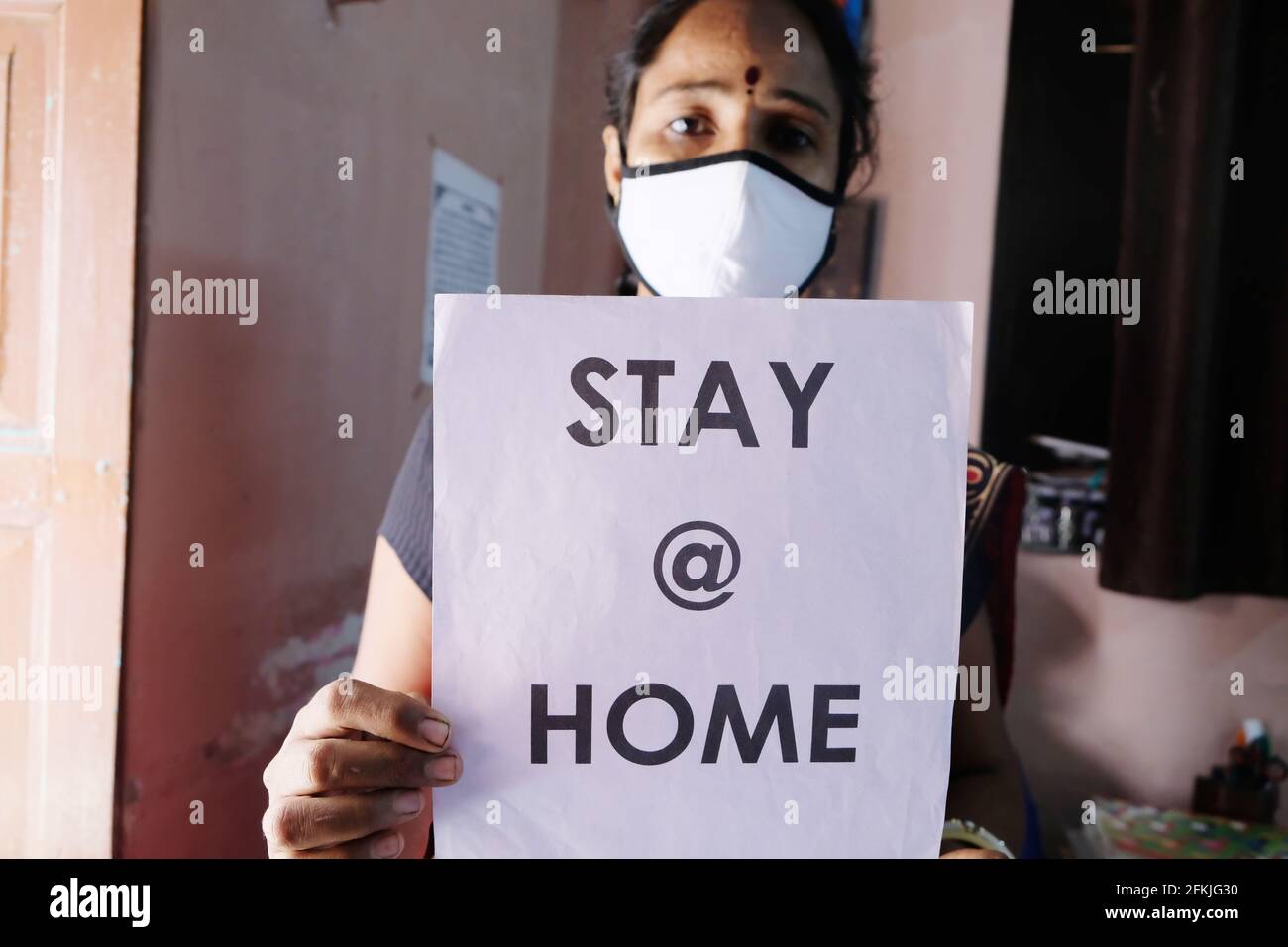 An Indian female holding a poster with the message "stay home" during ...