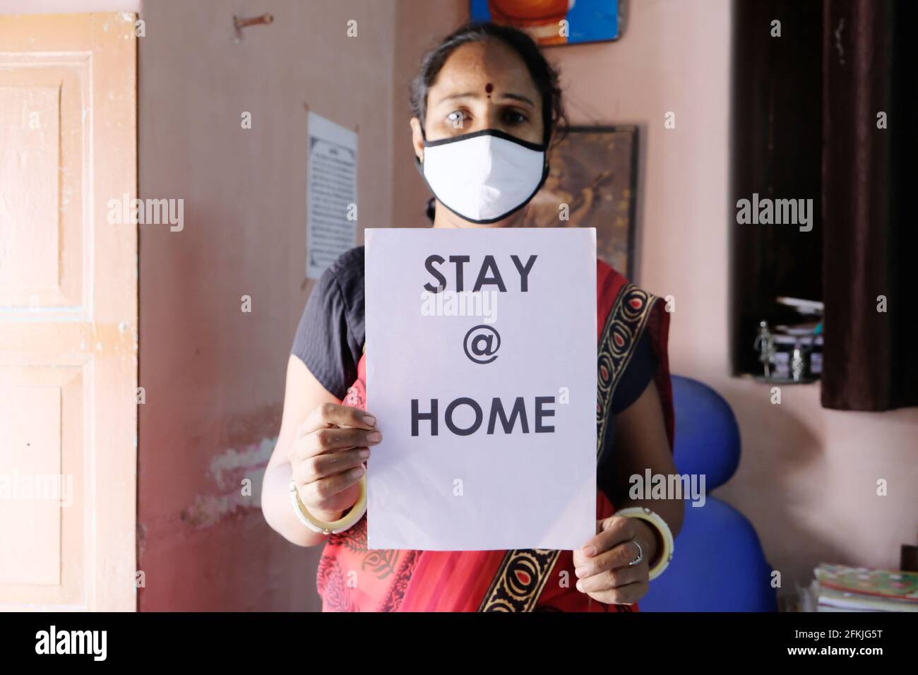 An Indian female holding a poster with the message "stay home" during ...