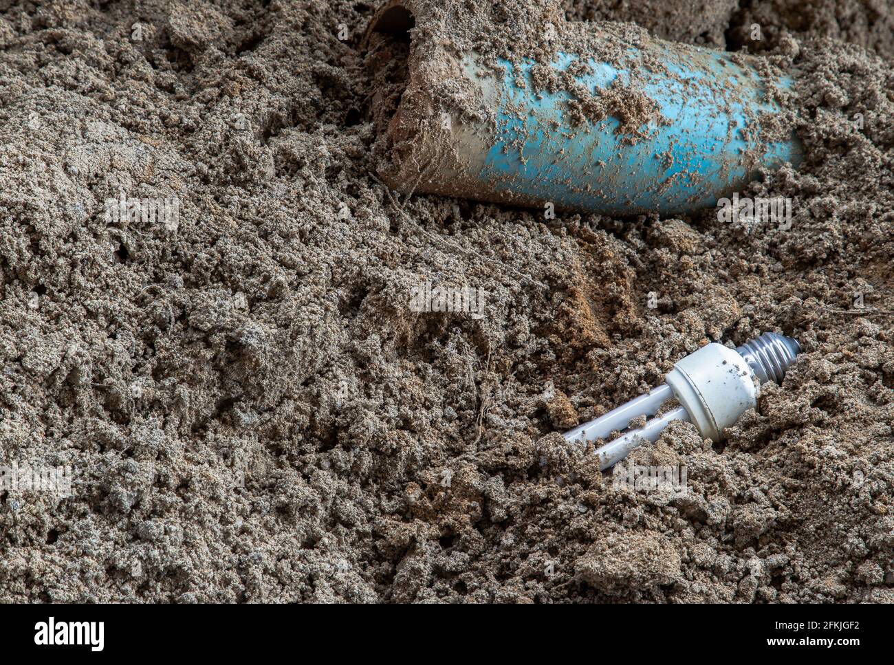 The remains of burnt energy-saving lamp are left on the beach sand ...