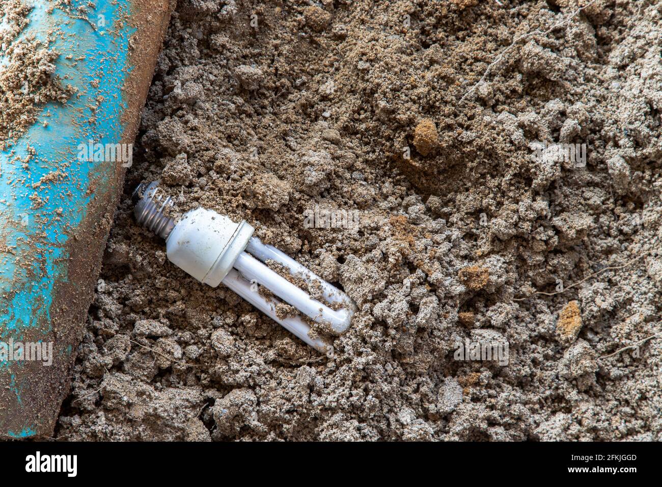 The remains of burnt energy-saving lamp are left on the beach sand ...