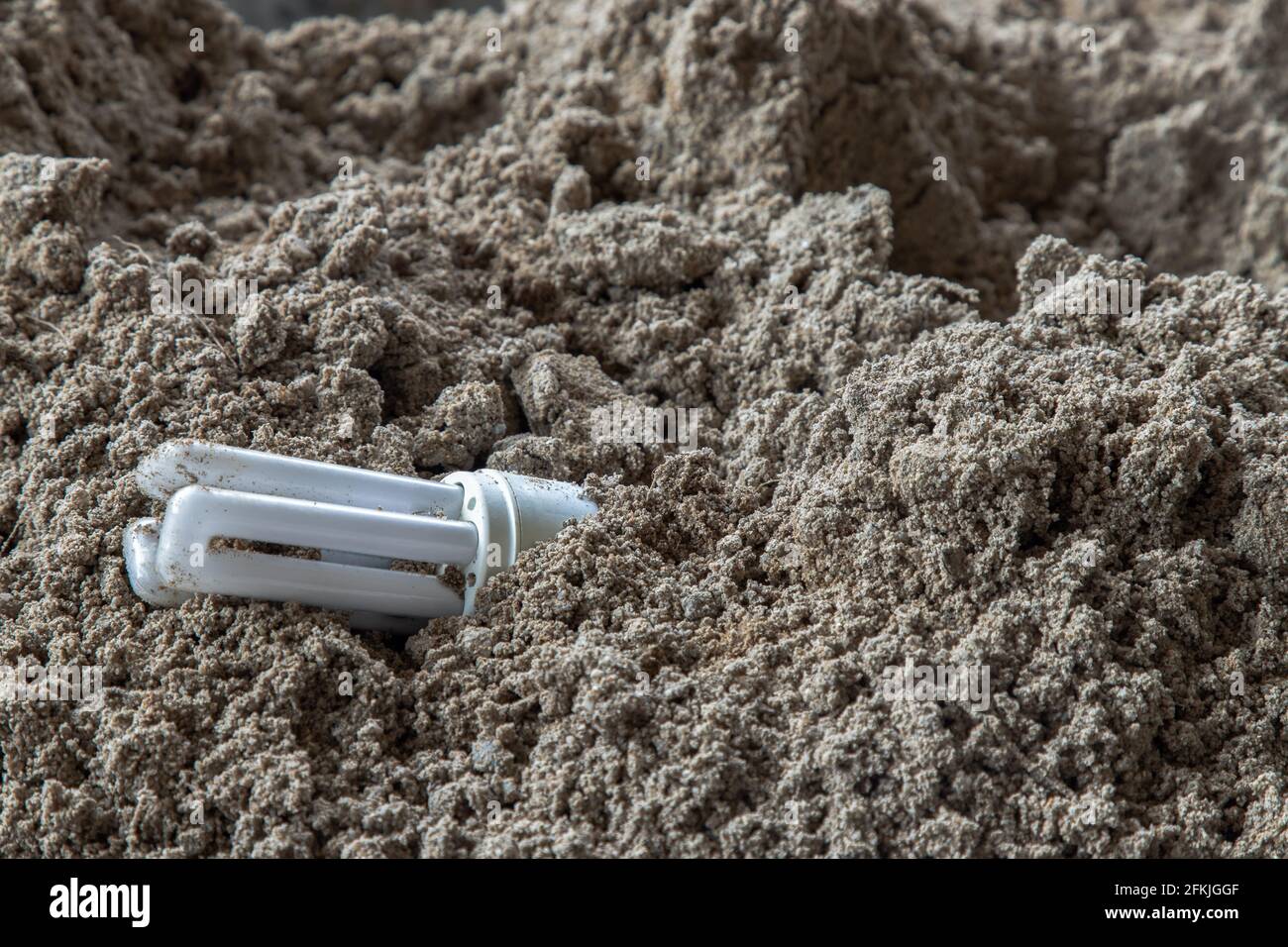 The remains of burnt energy-saving lamp are left on the beach sand ...