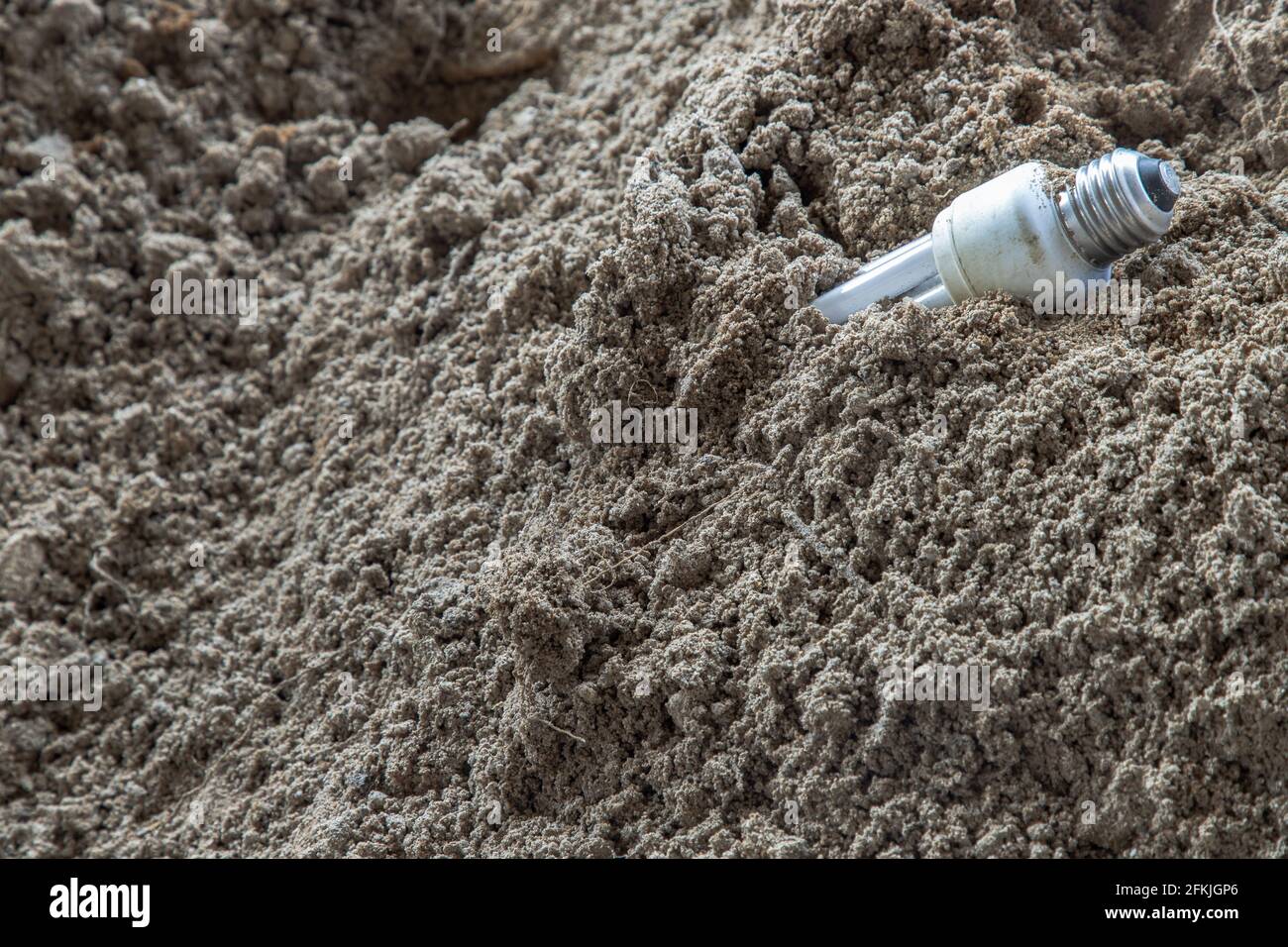The remains of burnt energy-saving lamp are left on the beach sand ...