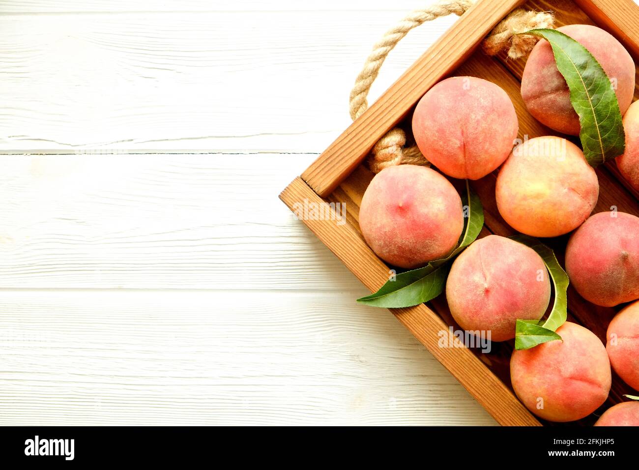 Bunch of ripe organic peaches in pile on wooden tray tray with rope ...