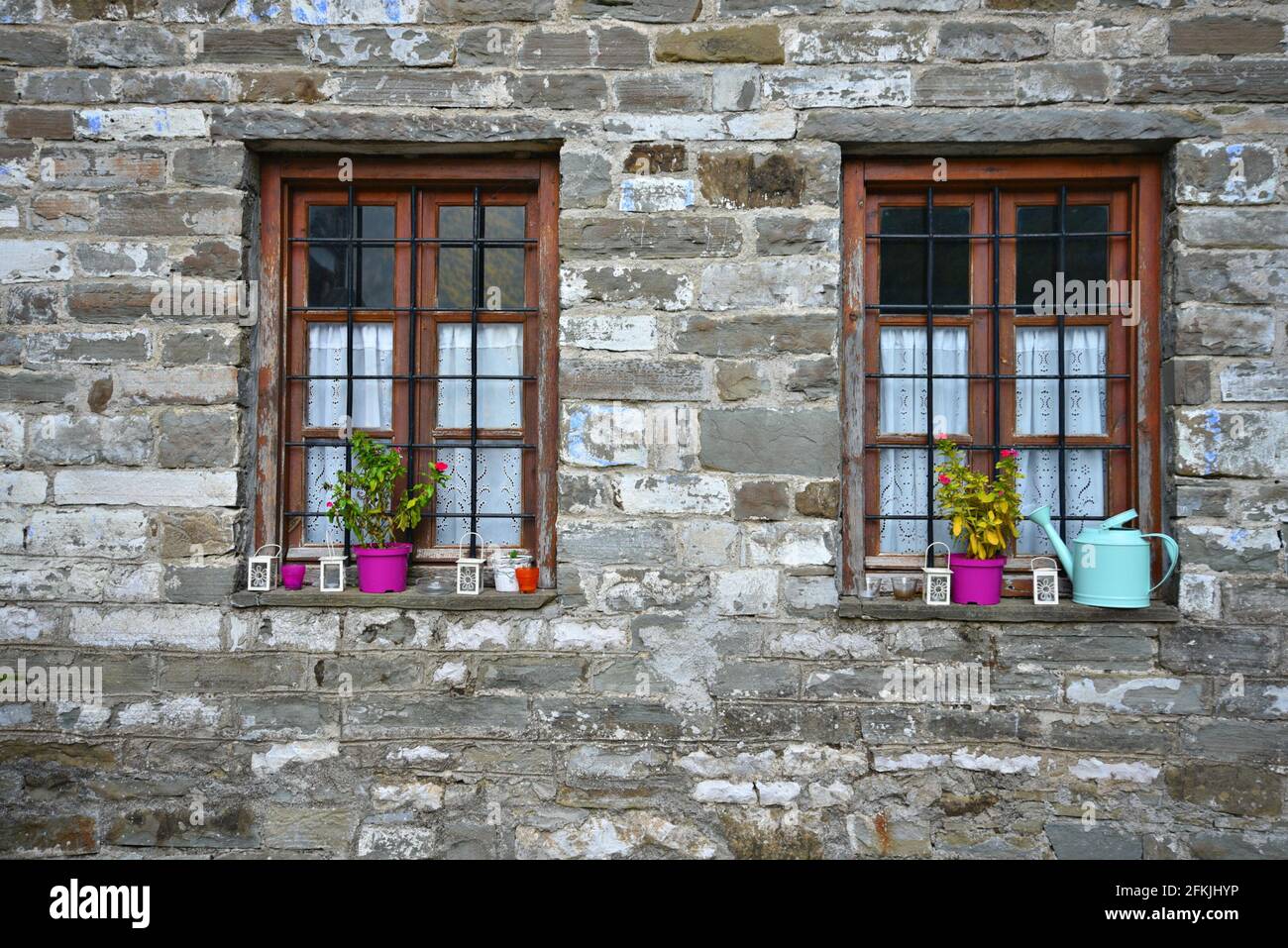 Traditional wooden windows with lace curtains and clay pots with ...