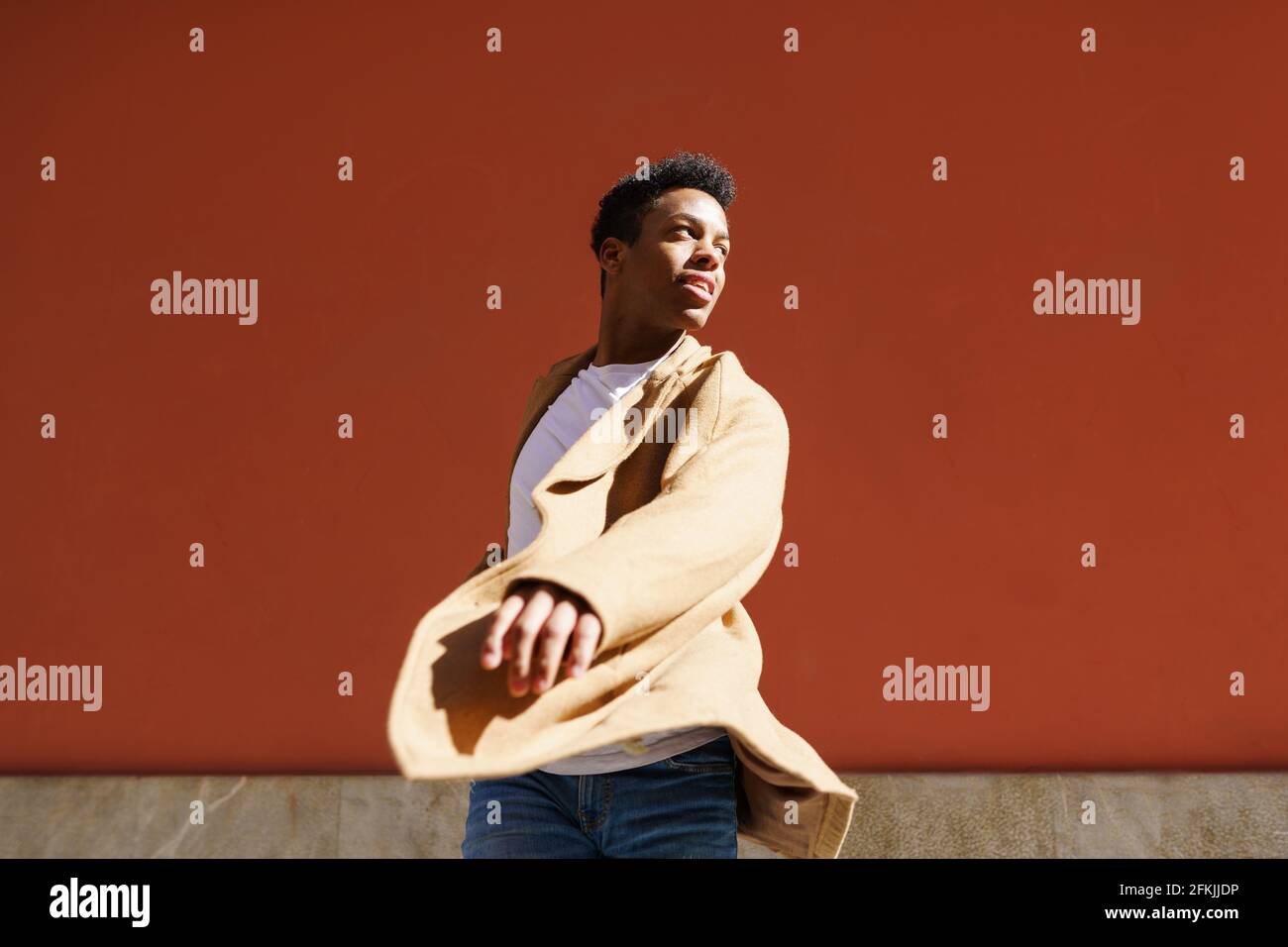 Young Cuban man dancing on red urban wall Stock Photo - Alamy