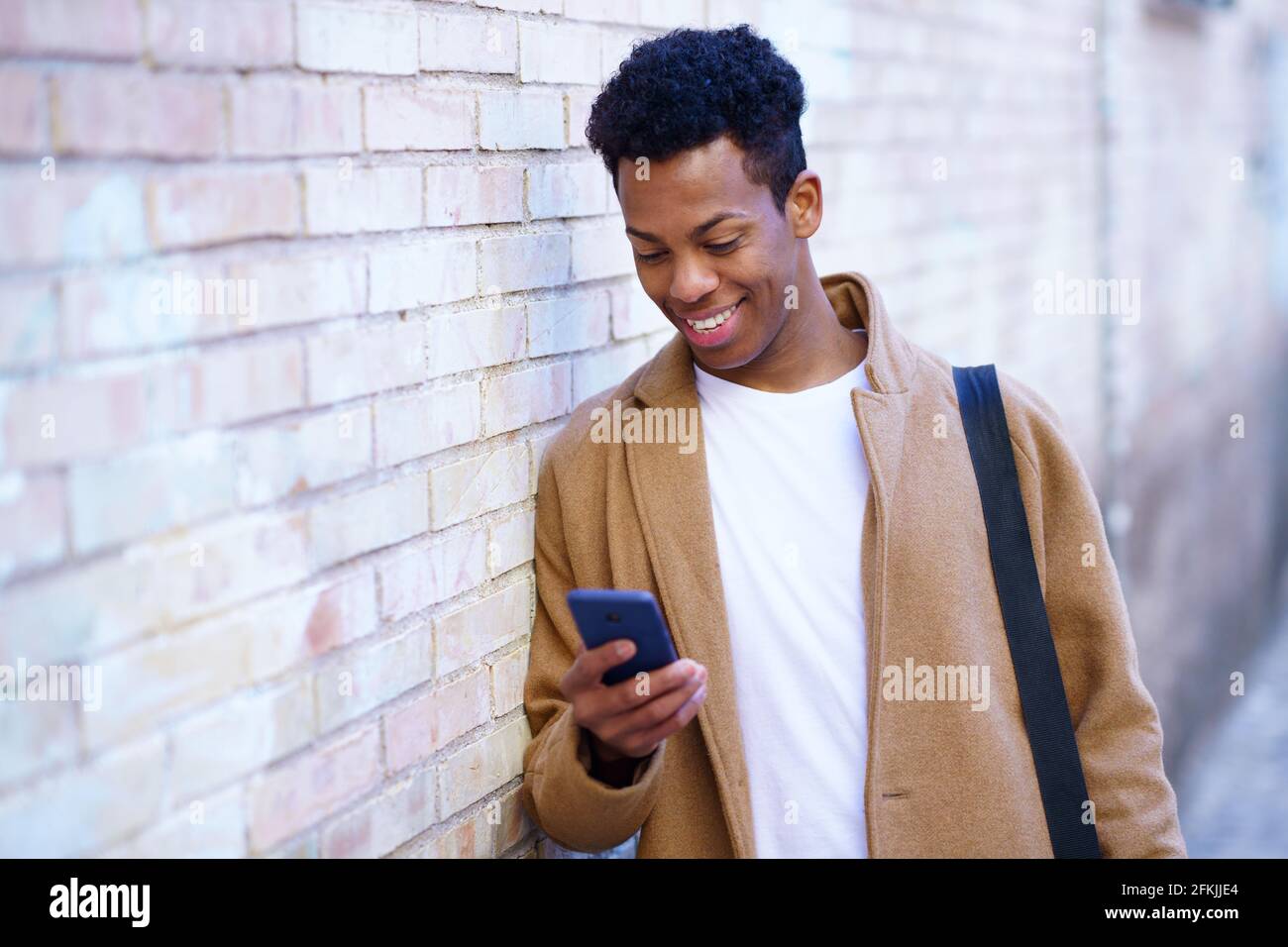 Cuban young man using a smartphone near a urban wall Stock Photo - Alamy