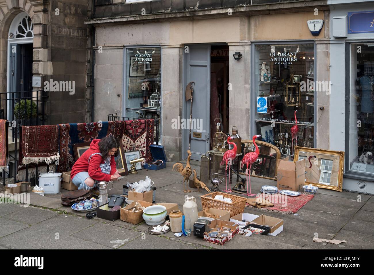 Young woman looking at items on display on the pavement outside ...