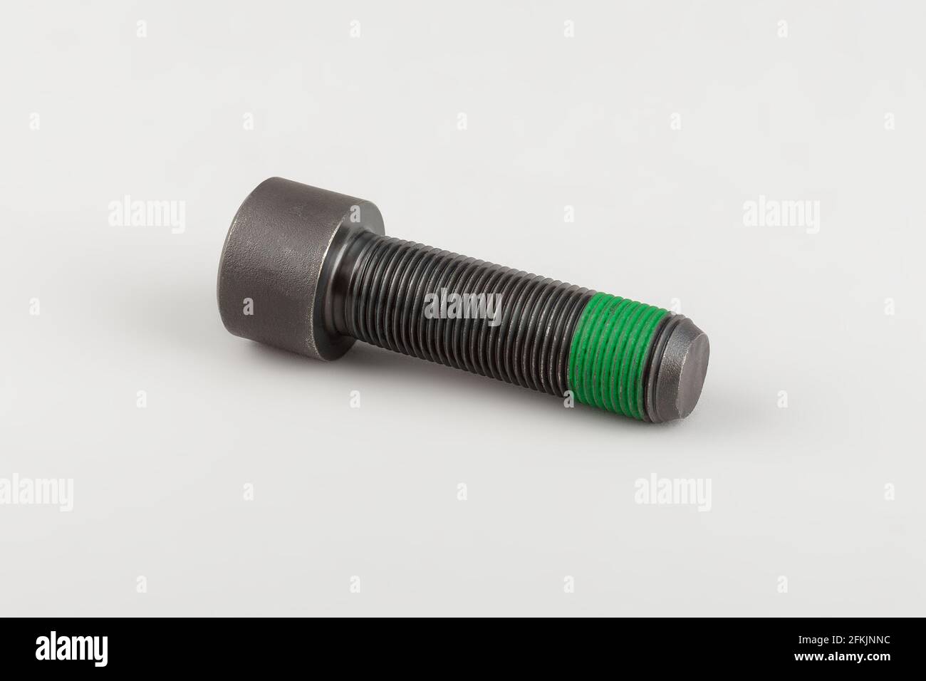 The flywheel bolt with the adhesive layer lies on a gray background ...