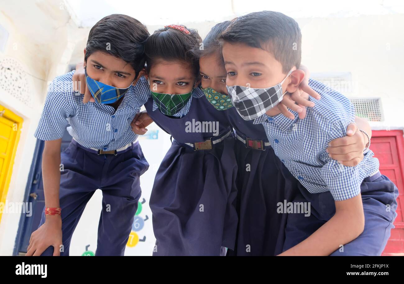 A group of Indian children in face masks and school uniforms taking a ...