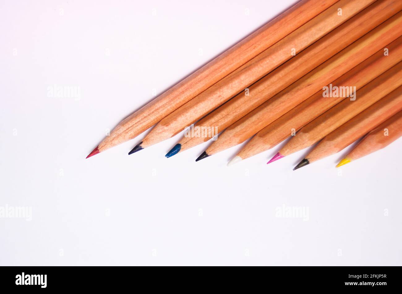 White background with a parallel arrangement of colored pencils With a ...