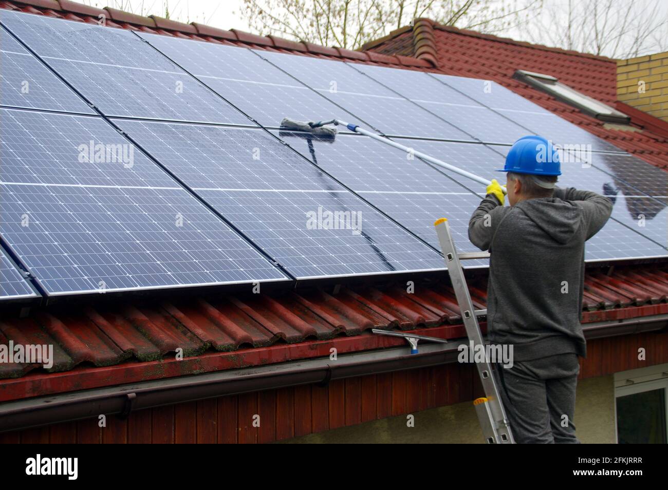 Cleaning solar panels. A man on a ladder cleans and washing a ...