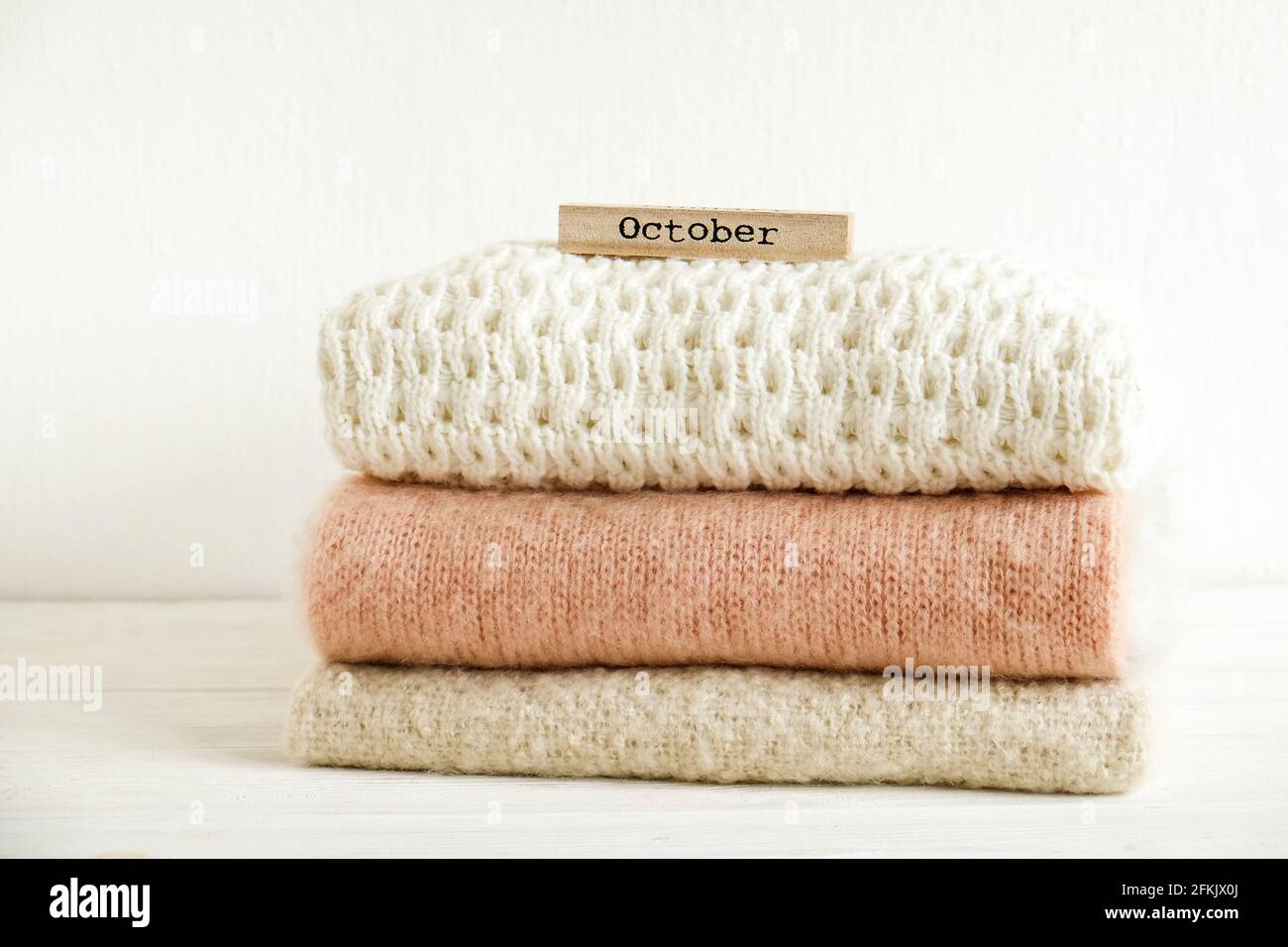 Word october written on wooden calendar, bunch of knitted warm pastel ...