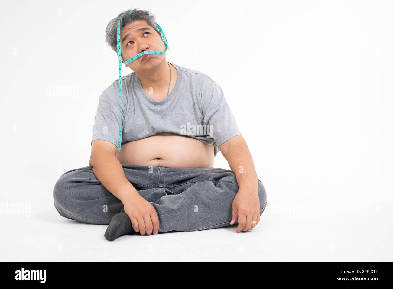 An overweight man sitting on the floor and Bored after uses a ...