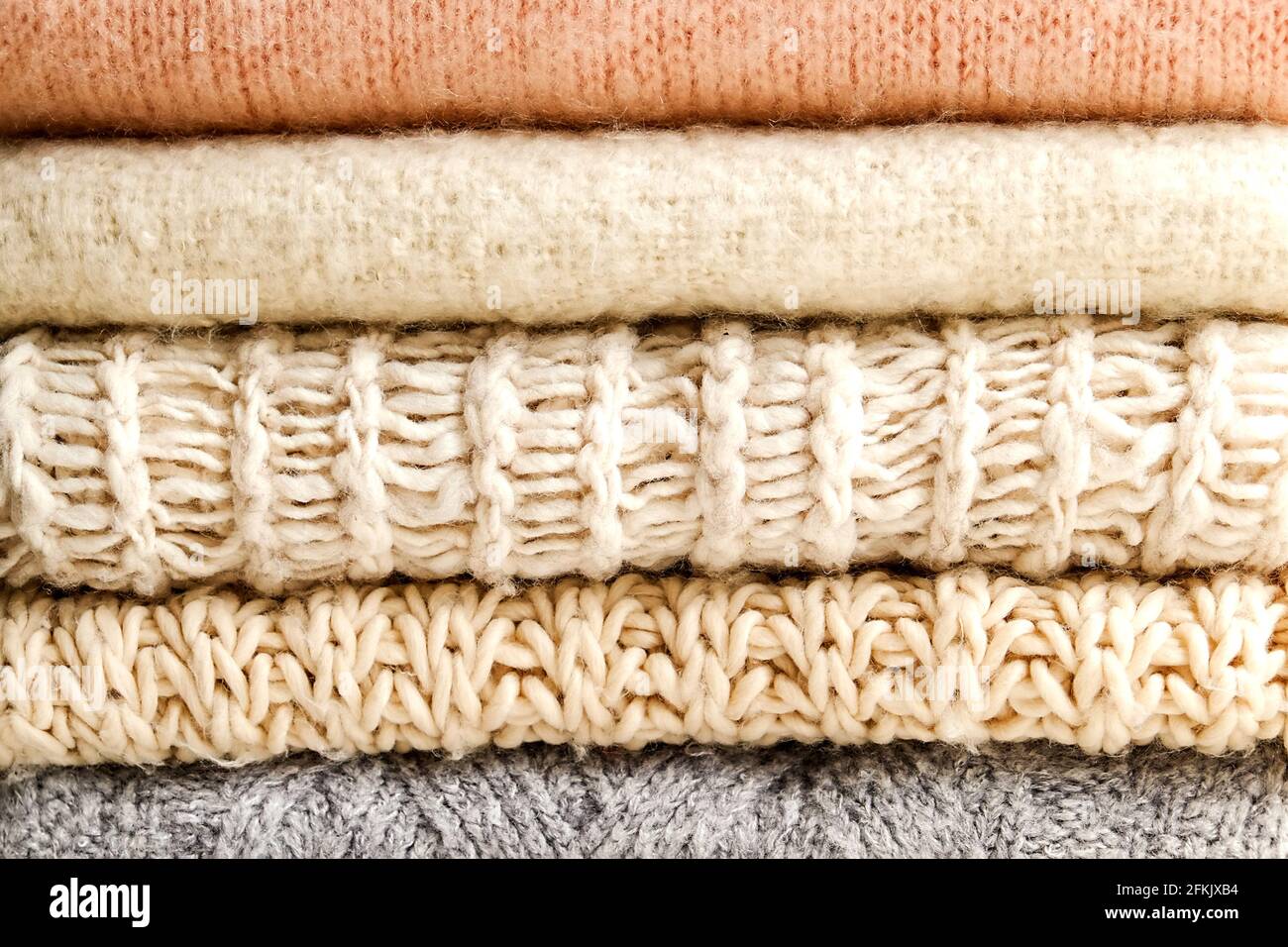 Bunch of knitted warm pastel color sweaters with different knitting ...