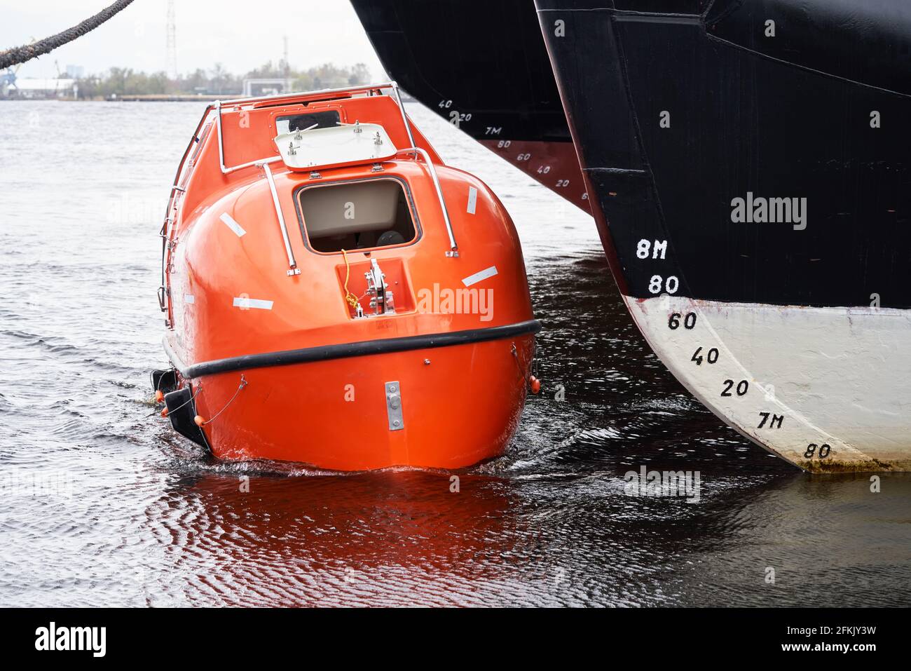 Totally Enclosed Lifeboat floating near big vessel Stock Photo - Alamy