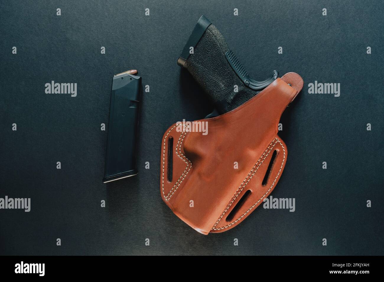 An isolated shot of a gun covered with leather holster on the table ...