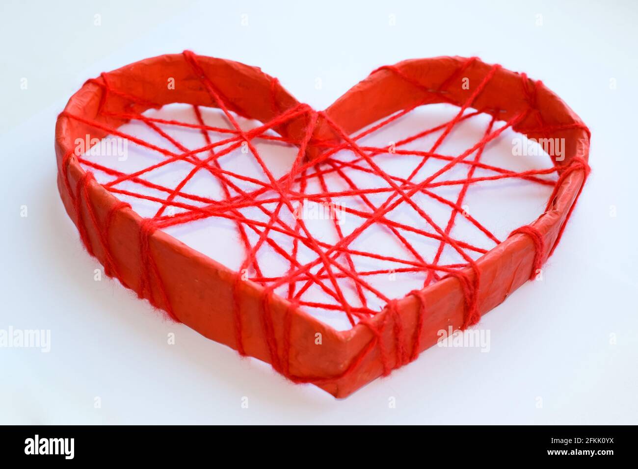 A paper heart tied with red threads. Heart on a white background Stock ...