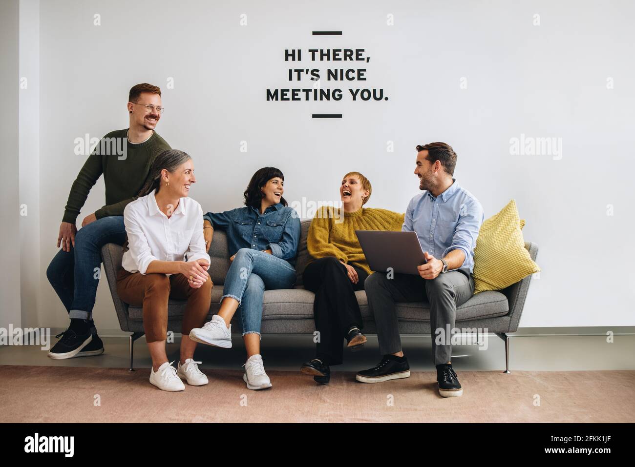 Smiling coworkers sitting and sharing ideas in office lobby. Team ...
