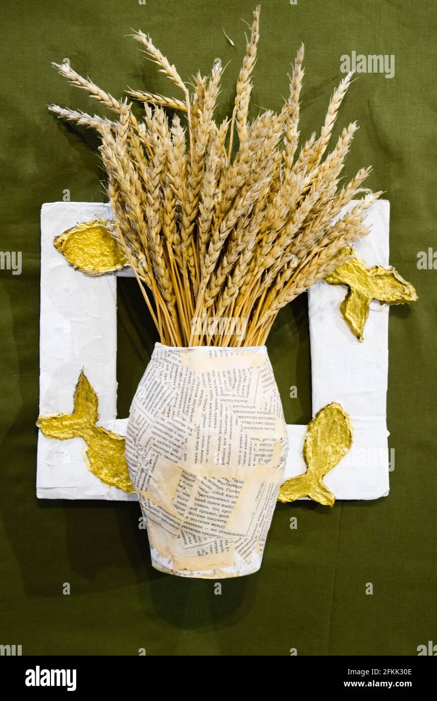 Cardboard vase from newspapers, in a vase of wheat. A photo frame with ...