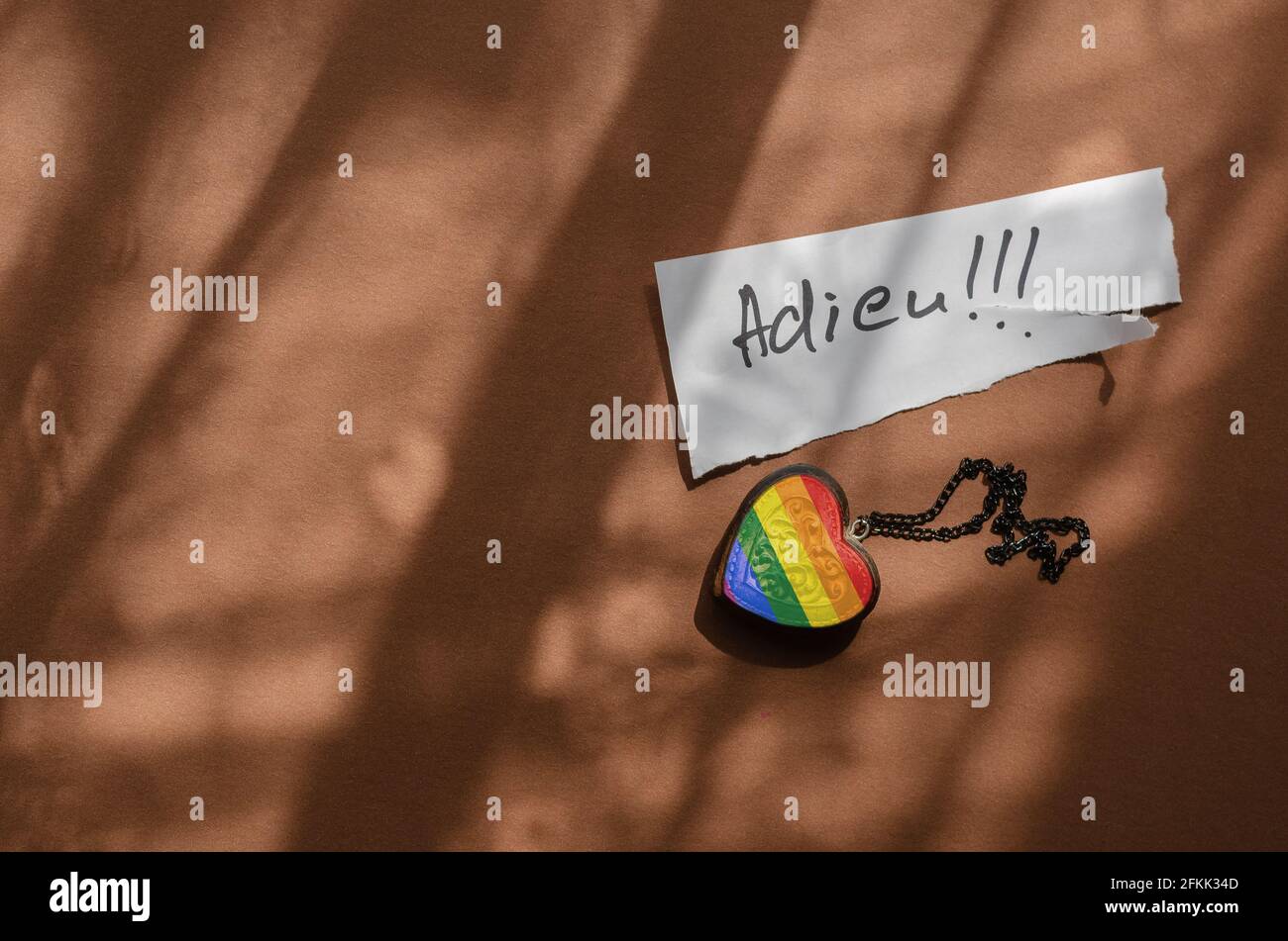 Handwritten word Adieu on a white piece of paper and a wooden amulet in ...