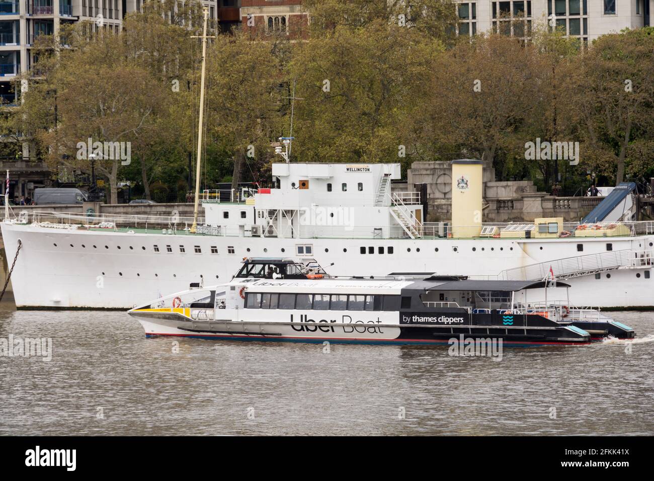 Uber Boat Thames clipper passes HQS Wellington on the River Thames ...
