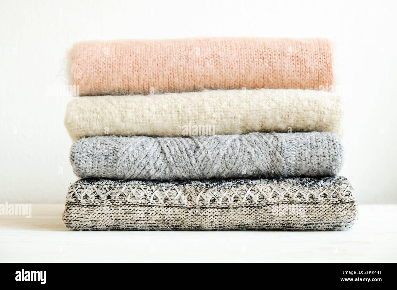 Bunch of knitted warm pastel color sweaters with different knitting ...