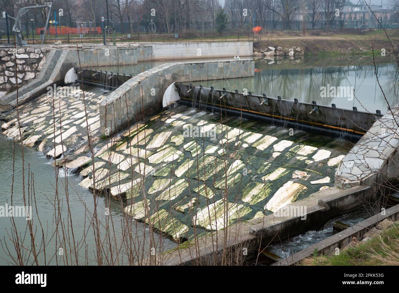 Small Rock Dam of a River in a Built-up Area Stock Photo - Alamy