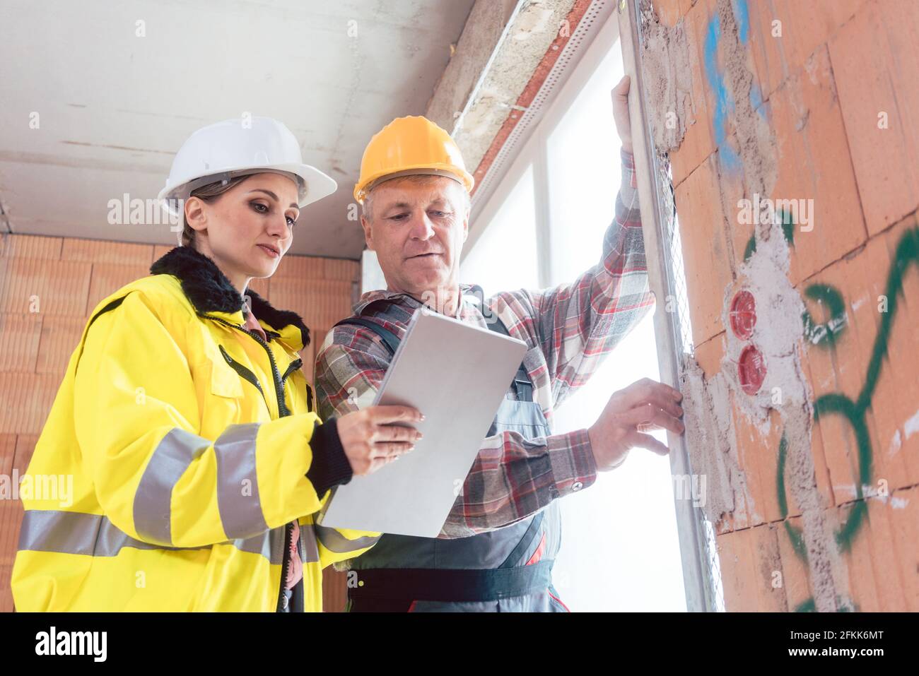 Construction worker checks a window panel wall with engineer using ...