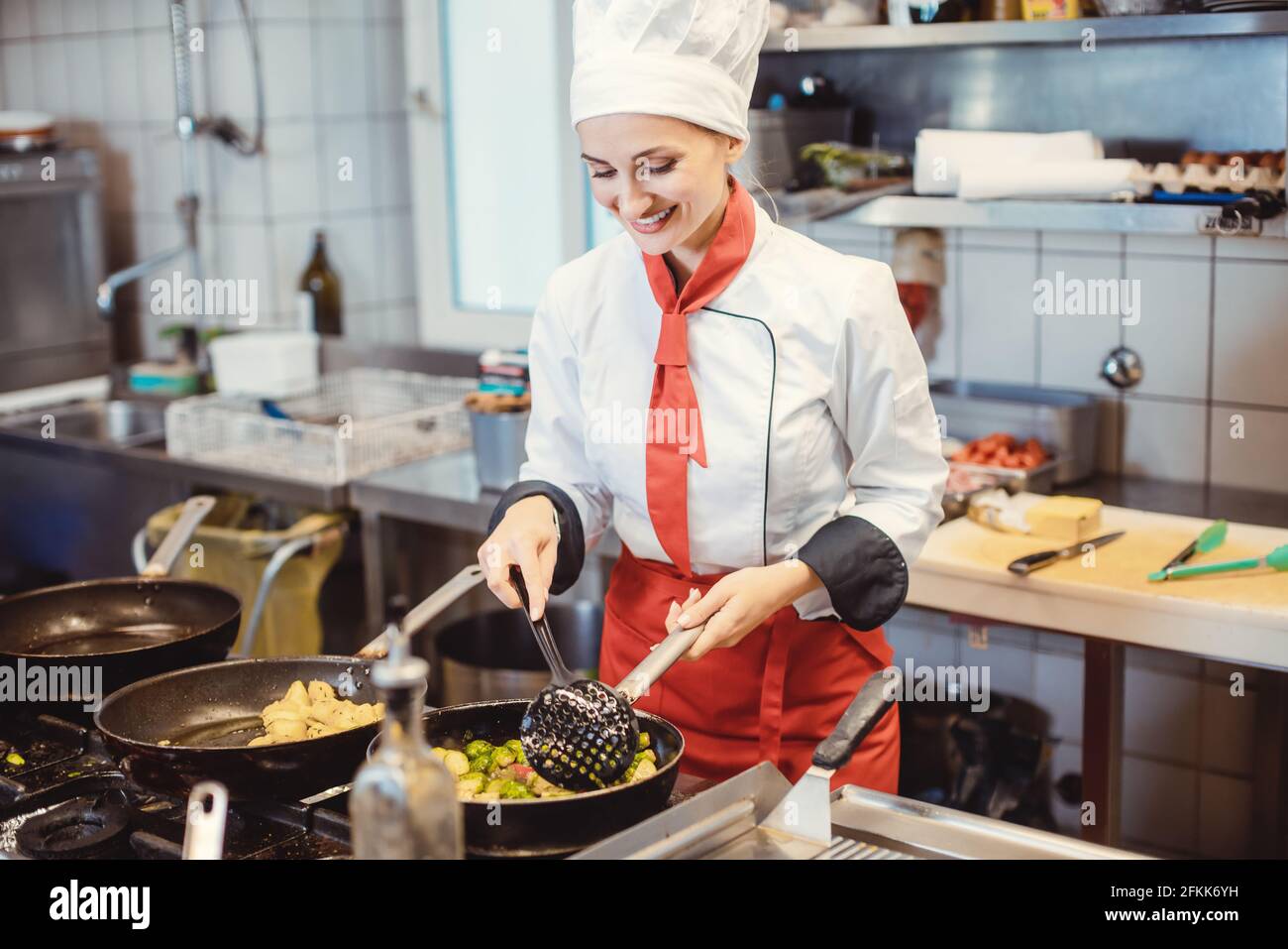 Woman chef with pans and pots preparing food in the restaurant kitchen ...
