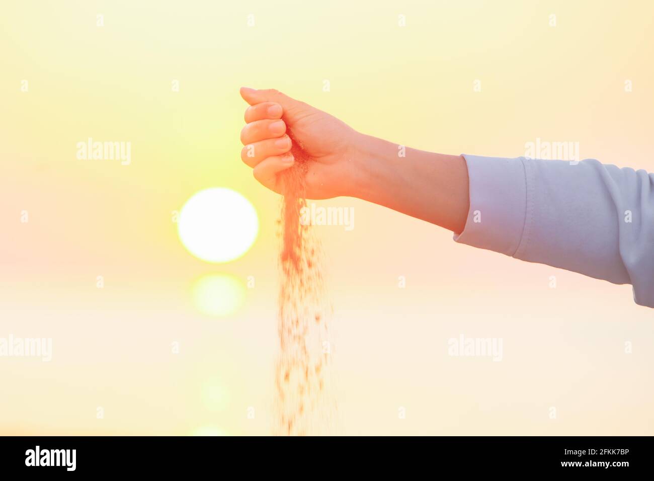 pouring sand from the woman hand on sunset Stock Photo - Alamy