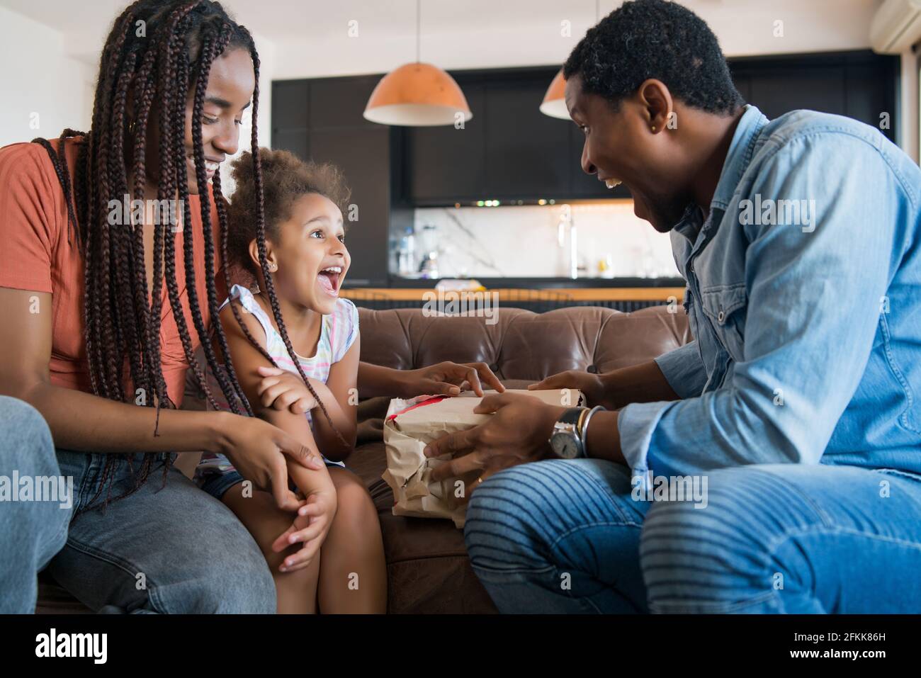 Little girl receiving gift from her parents Stock Photo - Alamy