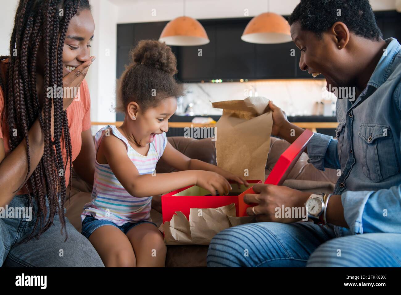 Little girl receiving gift from her parents Stock Photo - Alamy