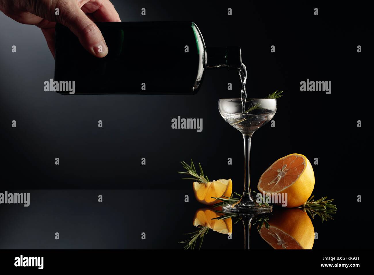 Gin is poured in a small glass from an antique bottle of dark glass. A ...