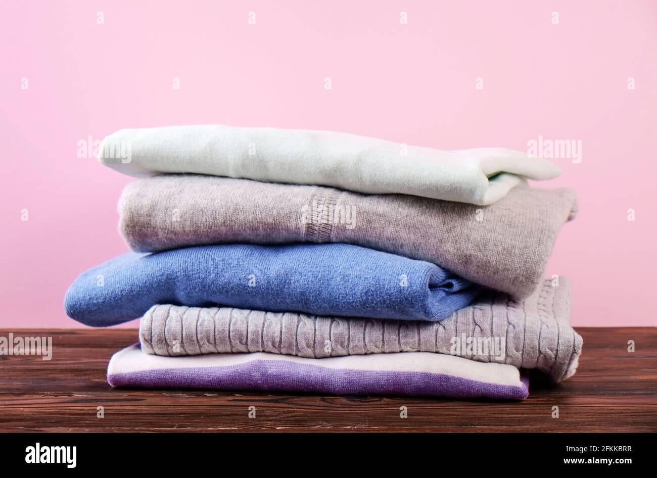 Stack of colorful perfectly folded sweaters on white wood texture table ...