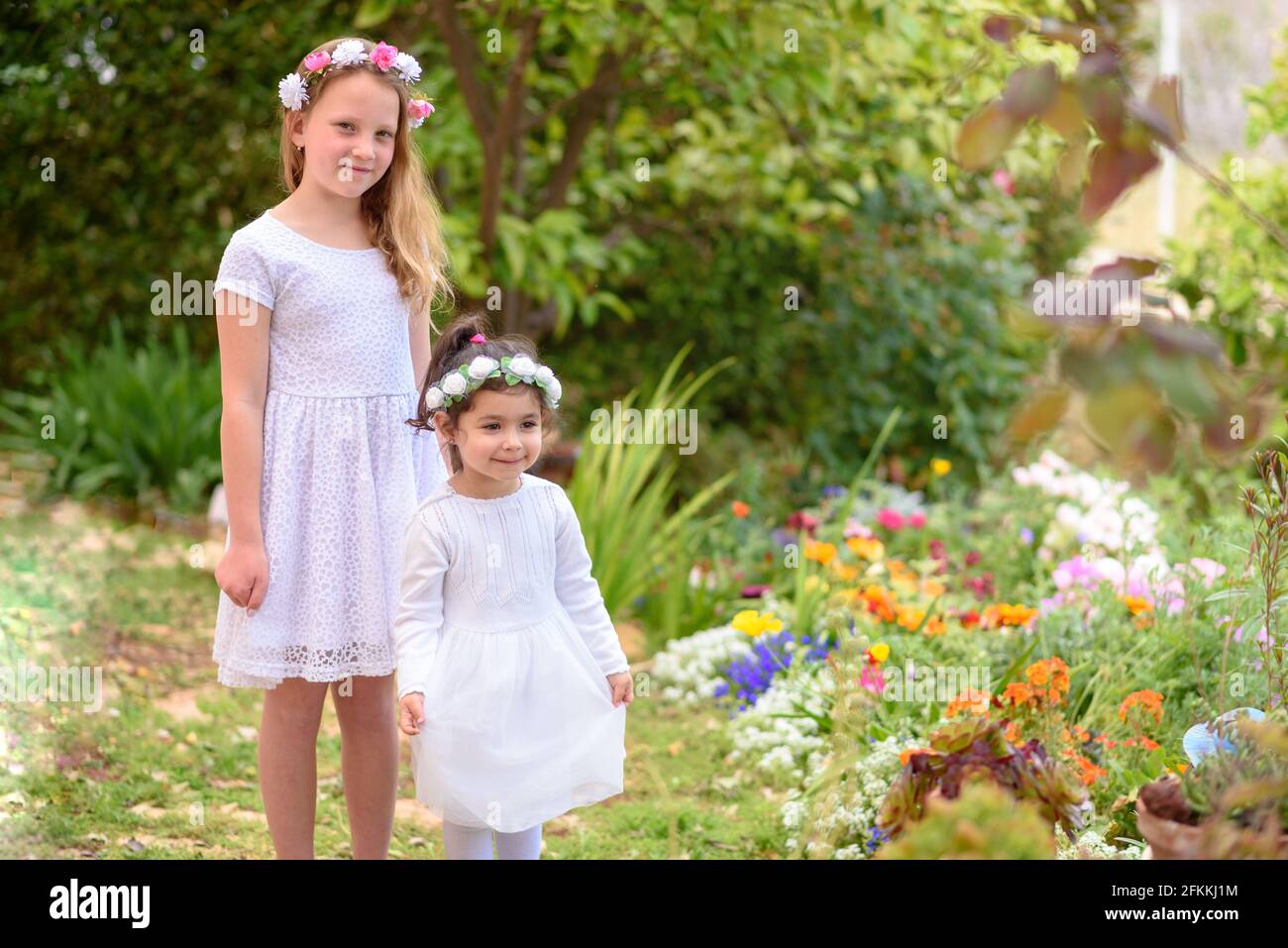Two happy multiracial children with white dress and flower wreath ...